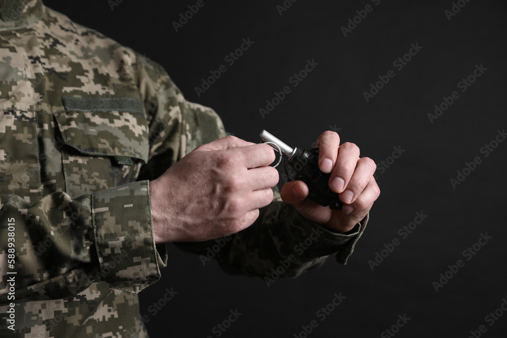 Soldier pulling safety pin out of hand grenade on black background ...