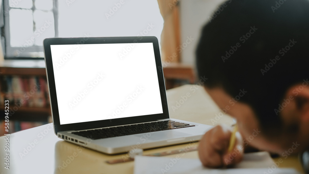 Blank screen laptop computer set up for work on wooden desk with boy ...