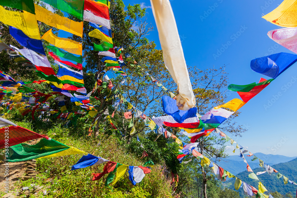 Flying colourful Buddhist religious prayer flags with green leaves and ...