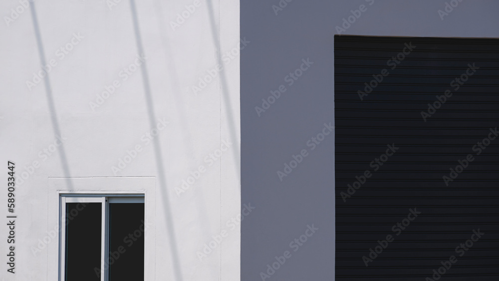 Sunlight and shadow on Glass sliding Window with roller shutter door of white warehouse building ...