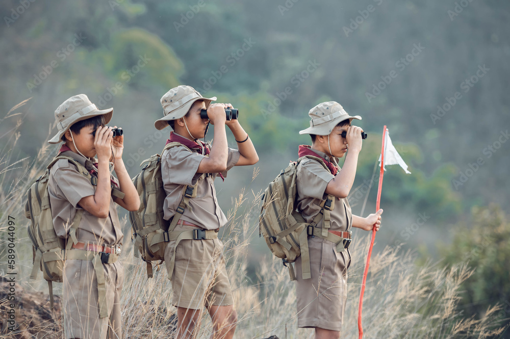 American Boy Scouts in uniform sit binoculars in a green field on a ...