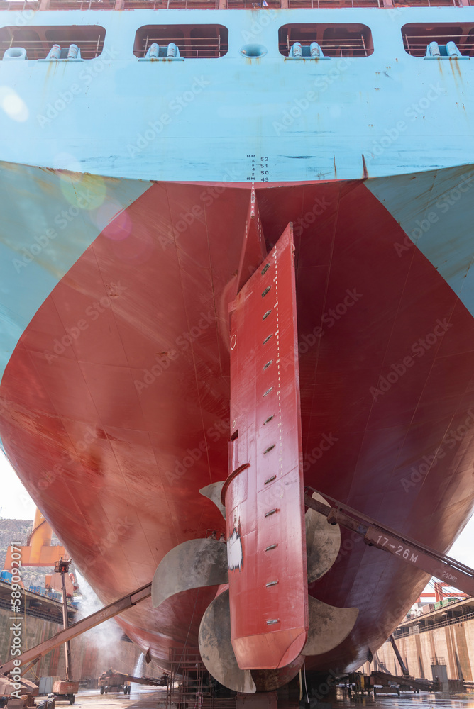 Back view on the container ship. Ship is inside a dry dock for routine ...