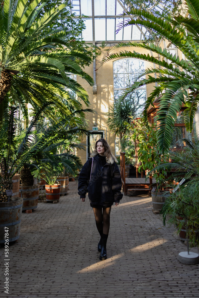 Young woman in botanical garden. She explore different types of trees ...