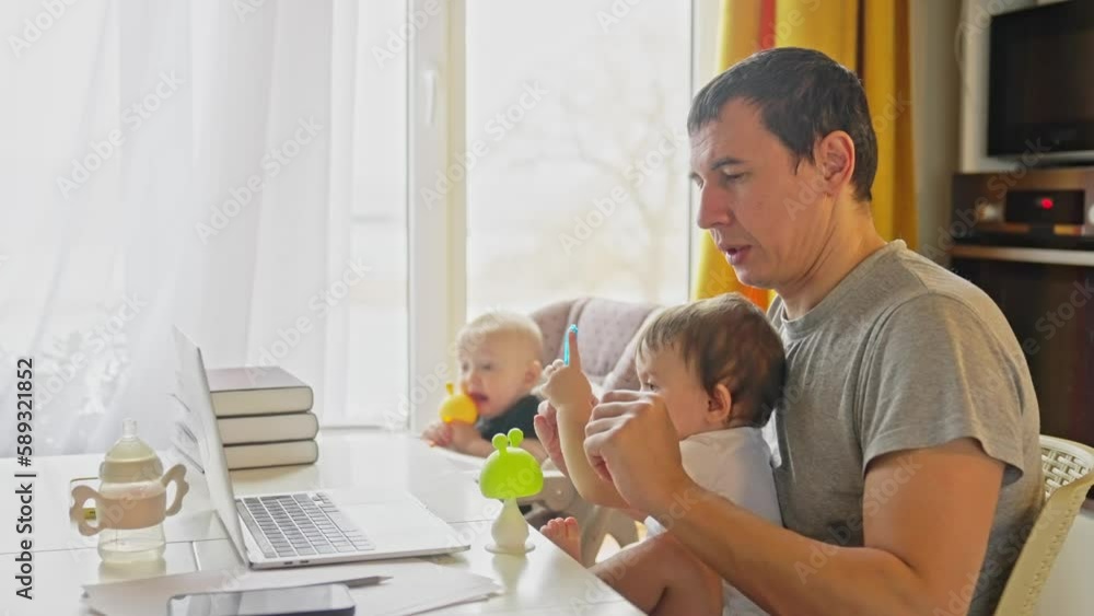 father working from home remotely with baby daughter in his arms ...