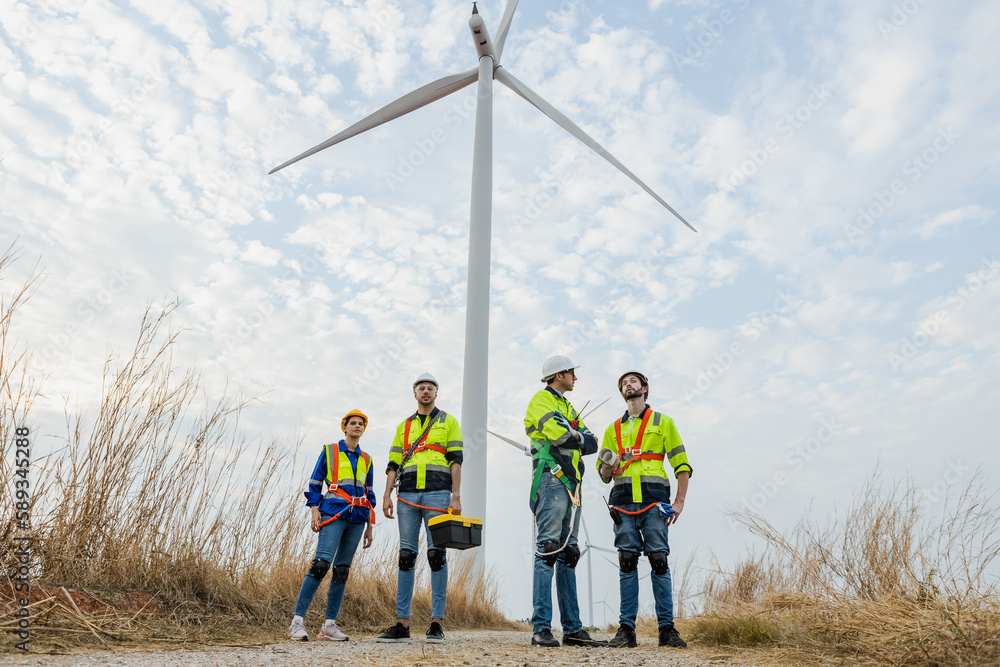 Teamwork engineer wearing safety uniform standing crossed arms at wind turbine field renewable ...