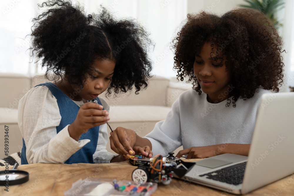 African American female and child girl building automatic toy car ...