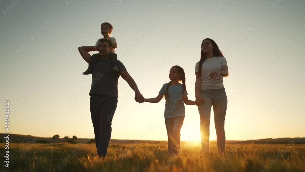 Happy family at sunset.People holding hands walk along green grass ...