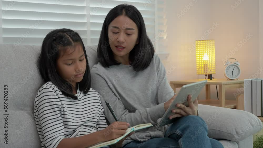 Mother teaching lesson for daughter. Asian young little girl learn at home. Do homework with ...