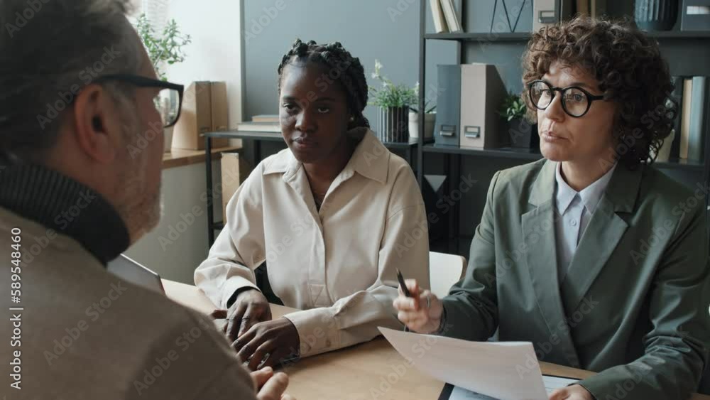 Over the shoulder shot of office where Caucasian woman having job ...