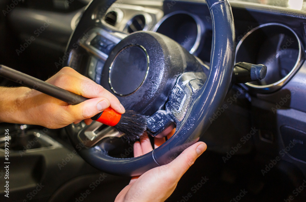 Car detailing and the concept of car interior care. A young man cleans ...