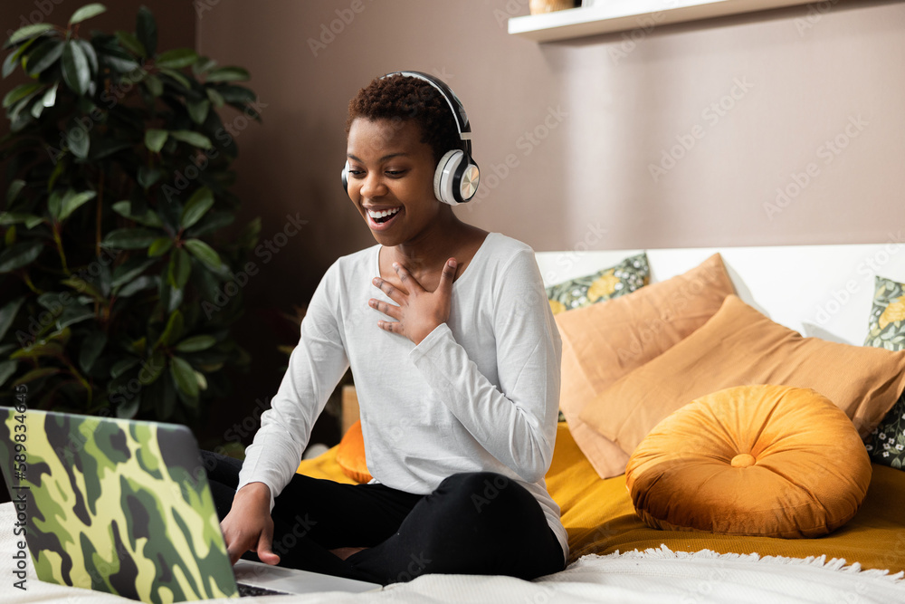 Curious delighted afro american woman sitting on bed wearing new ...