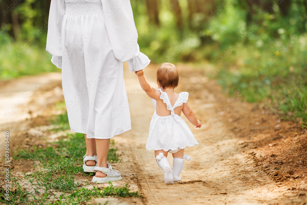 Little girl child is learning to walk. Mother teaches child to walk ...