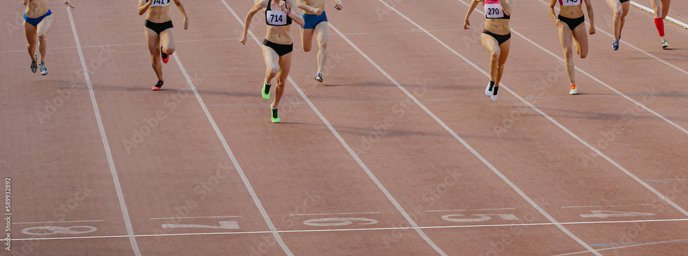 group female athletes run sprint race on stadium track, woman runner ...