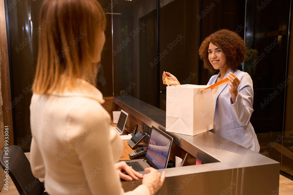 Beautiful female client unpacks packet at check in desk Stock Photo ...