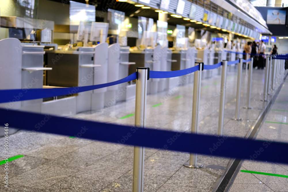 lobby of airport, blue barrier tape separates check-in counters for a ...