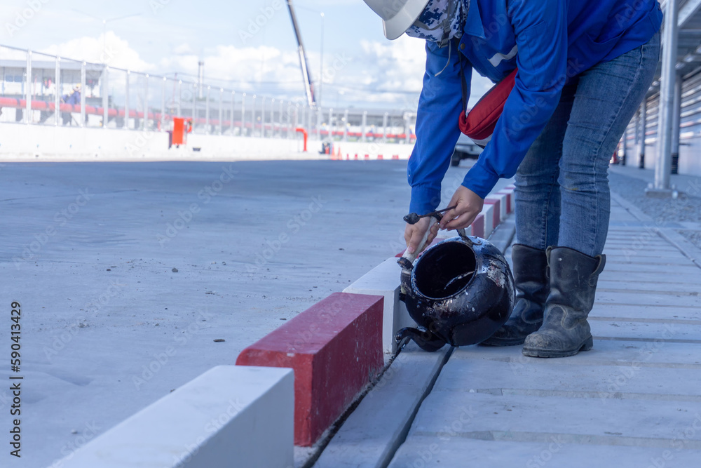 Worker sealing asphaltic joint for construction joint on concrete ...
