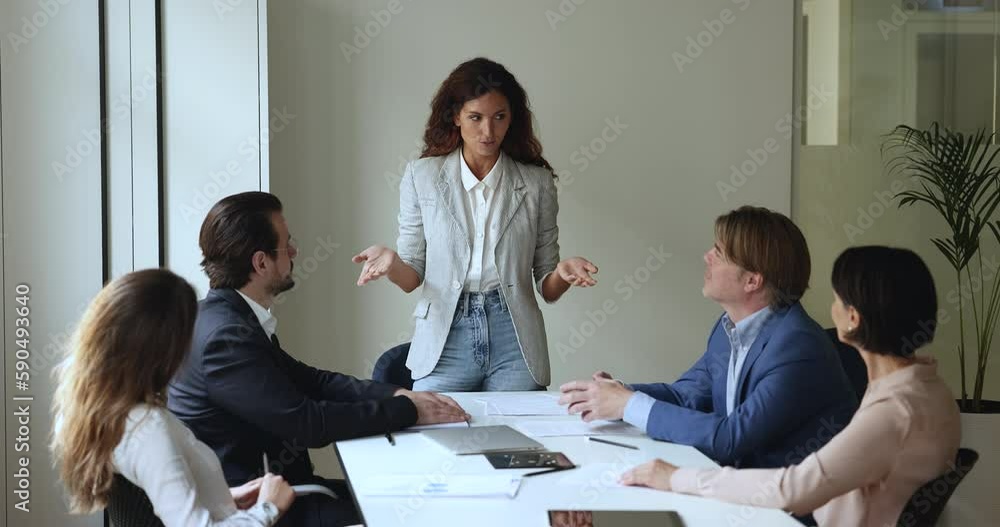 Serious beautiful business leader woman talking to team, standing at ...