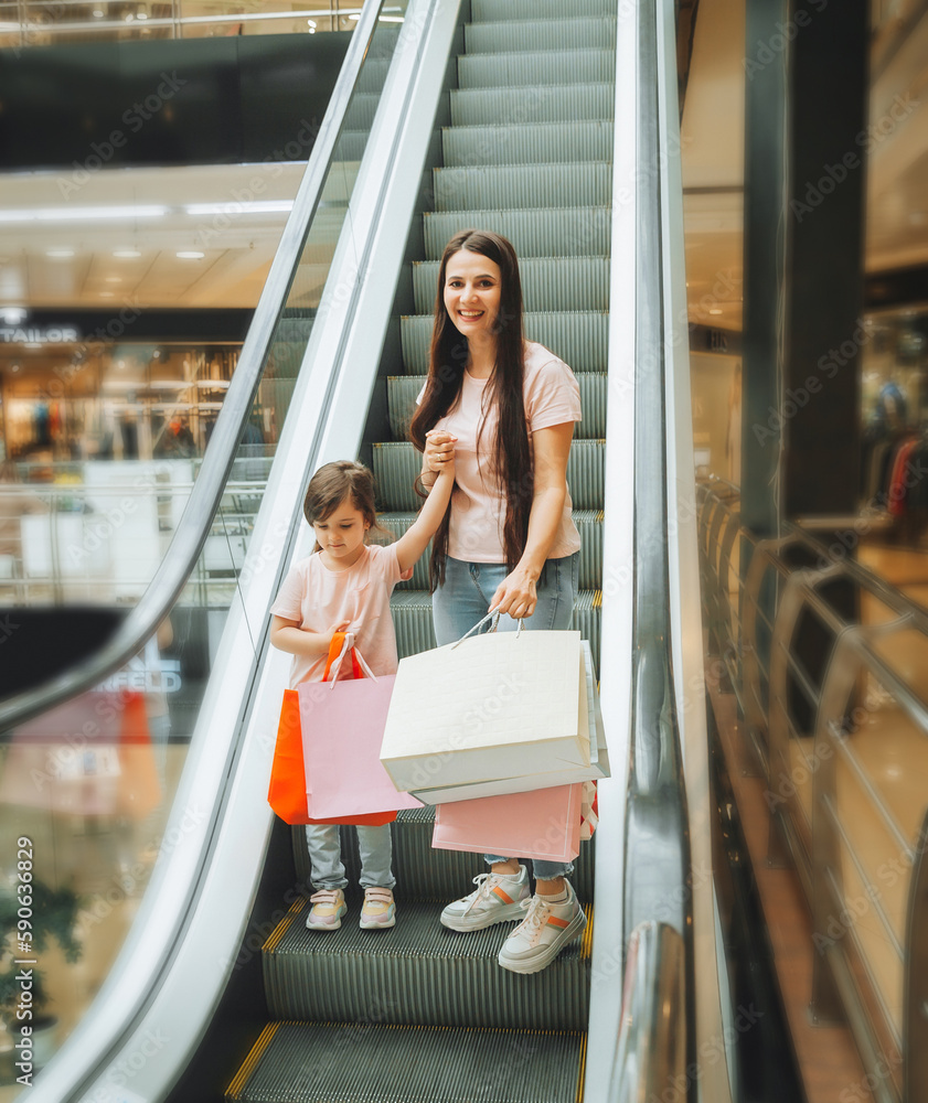mother and little girl on the escalator in the mall.Mother and daughter ...