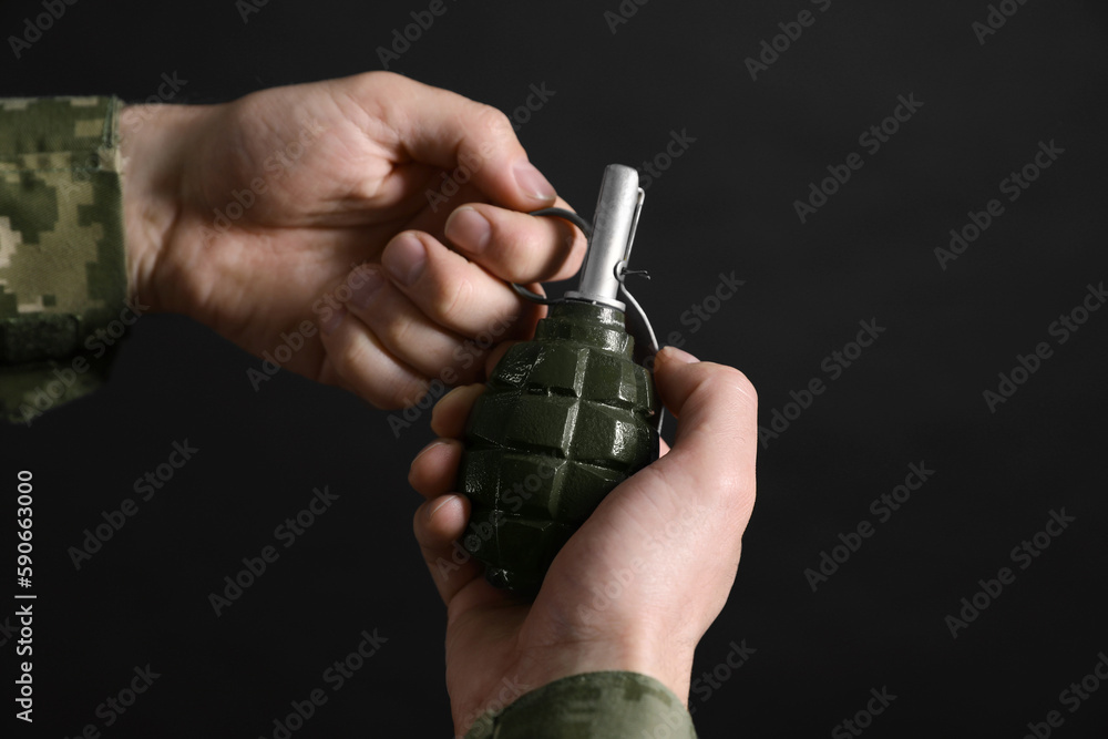 Soldier pulling safety pin out of hand grenade on black background ...