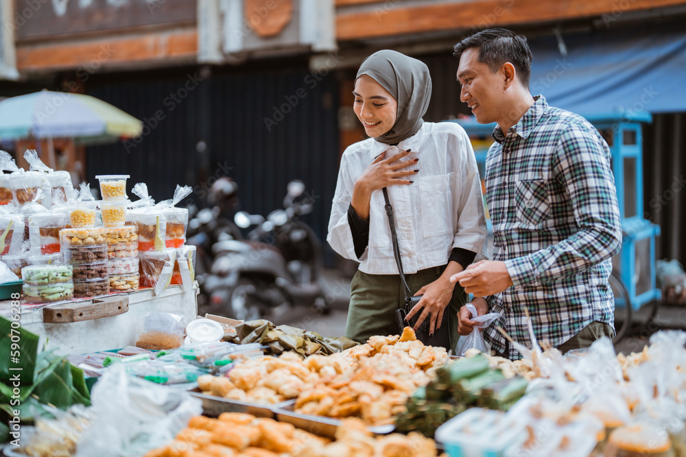 beautiful muslim woman and man are shopping in a food stall or street ...