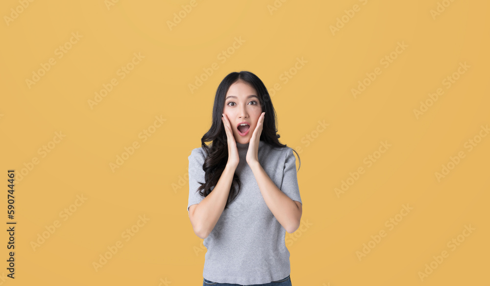 Young Asian doing a shocked surprise gesture with her hands on her face ...