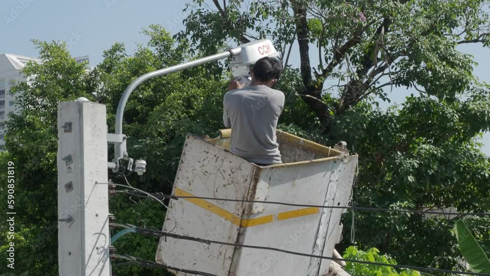Worker on height lifting platform installing new street light bulb ...