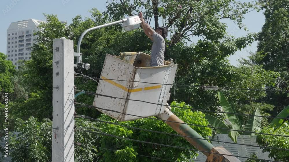Worker on height lifting platform installing new street light bulb ...