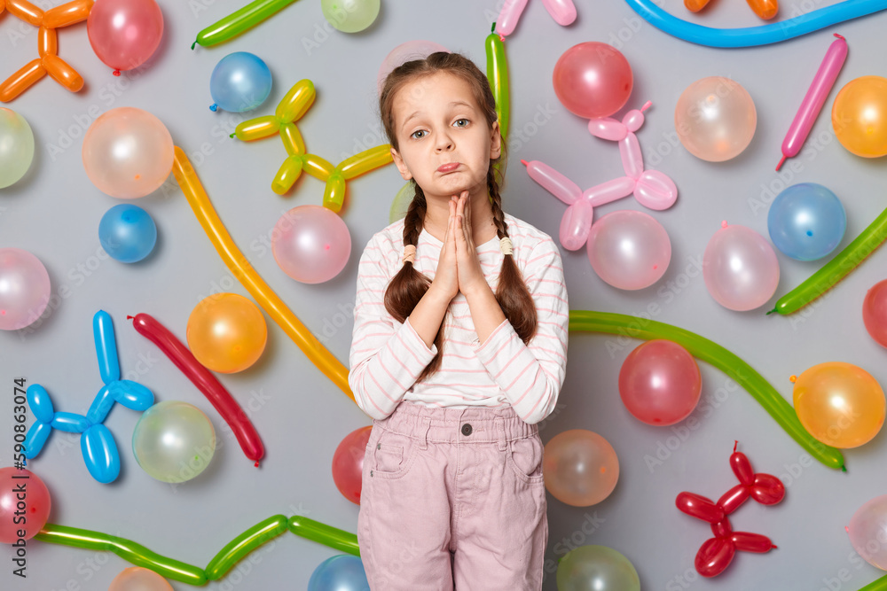 Pleading child. Sad upset little girl with pigtails standing against ...