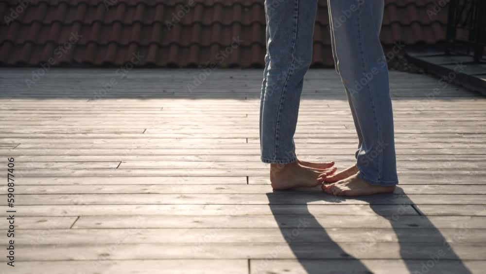 Legs barefoot of woman in jeans on toes playfully approach legs of man ...