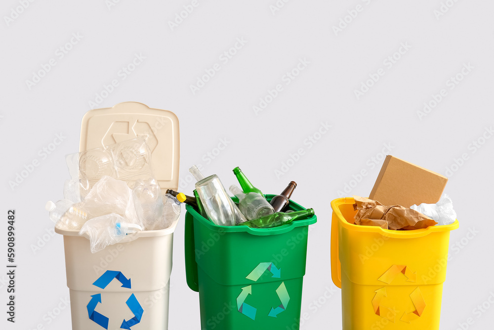 Containers with different types of garbage on light background ...