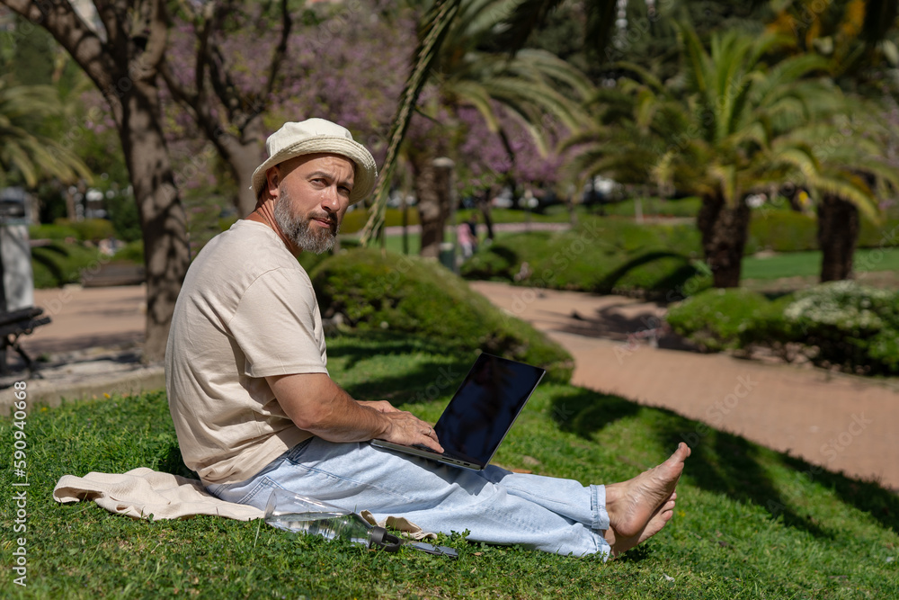 a bearded male freelancer with bare feet works on a laptop while ...