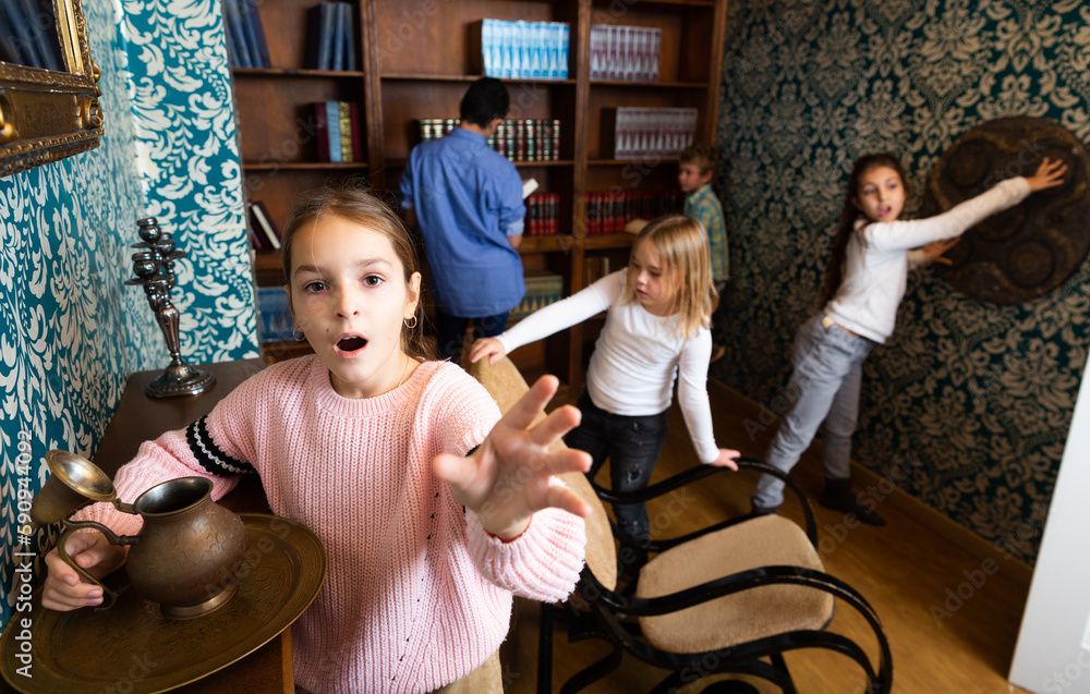 Interested tween girl trying to reach for some item in escape room ...