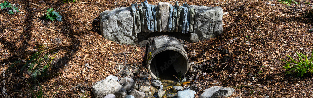 Old wooden stormwater pipe with new stone arch, rainwater flowing into ...