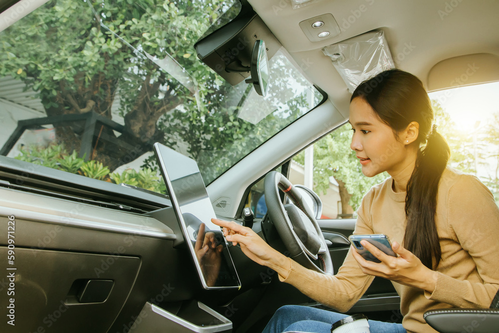 Side view young asian woman driving an EV electric vehicle sits in the ...