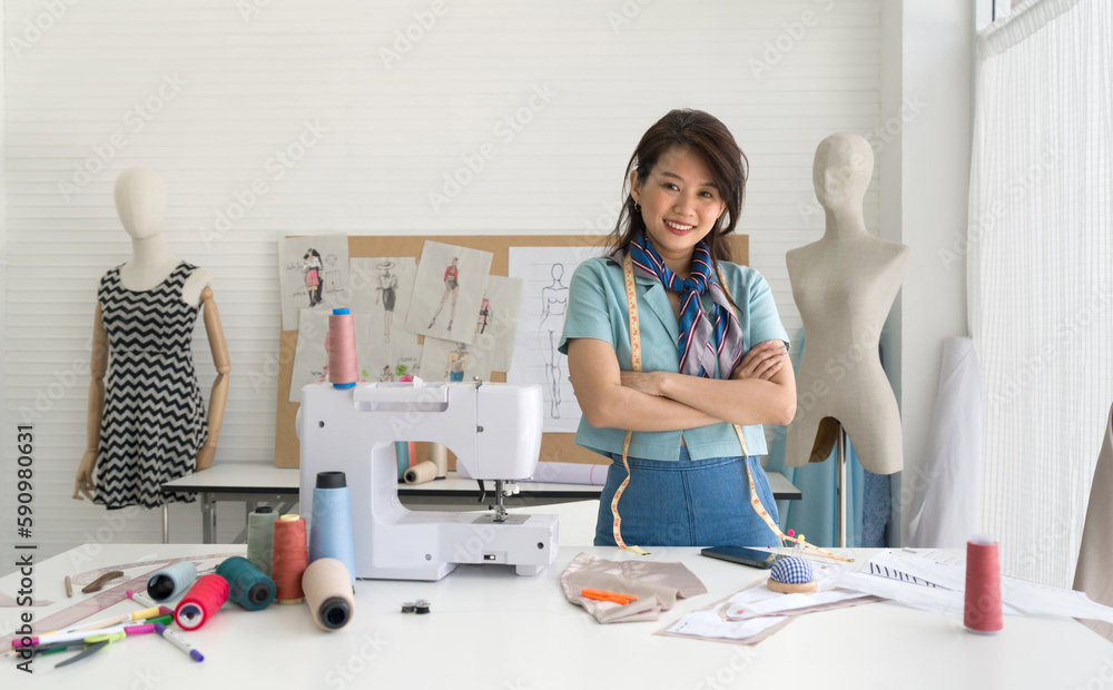 Young dressmaker with tape measure stand smiling with arms crossed ...