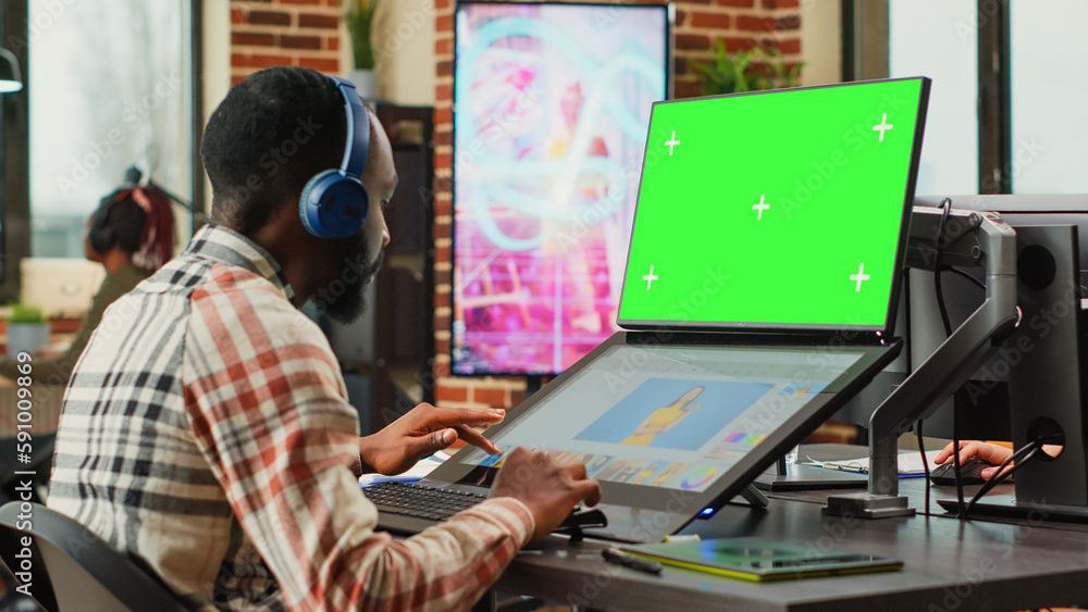 African american editor using greenscreen template on monitor, retouching photos with editing ...