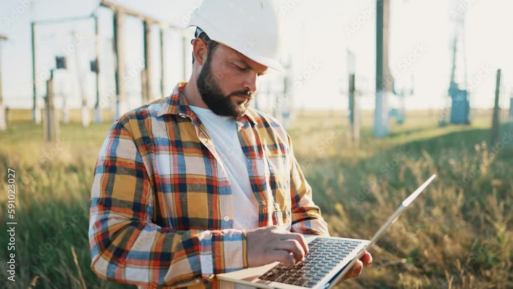 Stockvideon Engineer walk on field with electricity towers. Electrical ...
