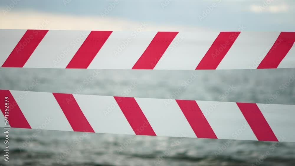 Red white warning tape barrier ribbon swinging in the wind across ...