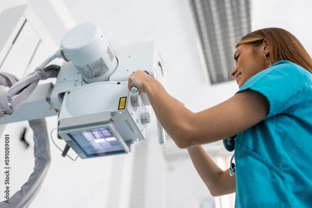Doctor looking at X-ray machine in clinic. Female doctor sets up the ...