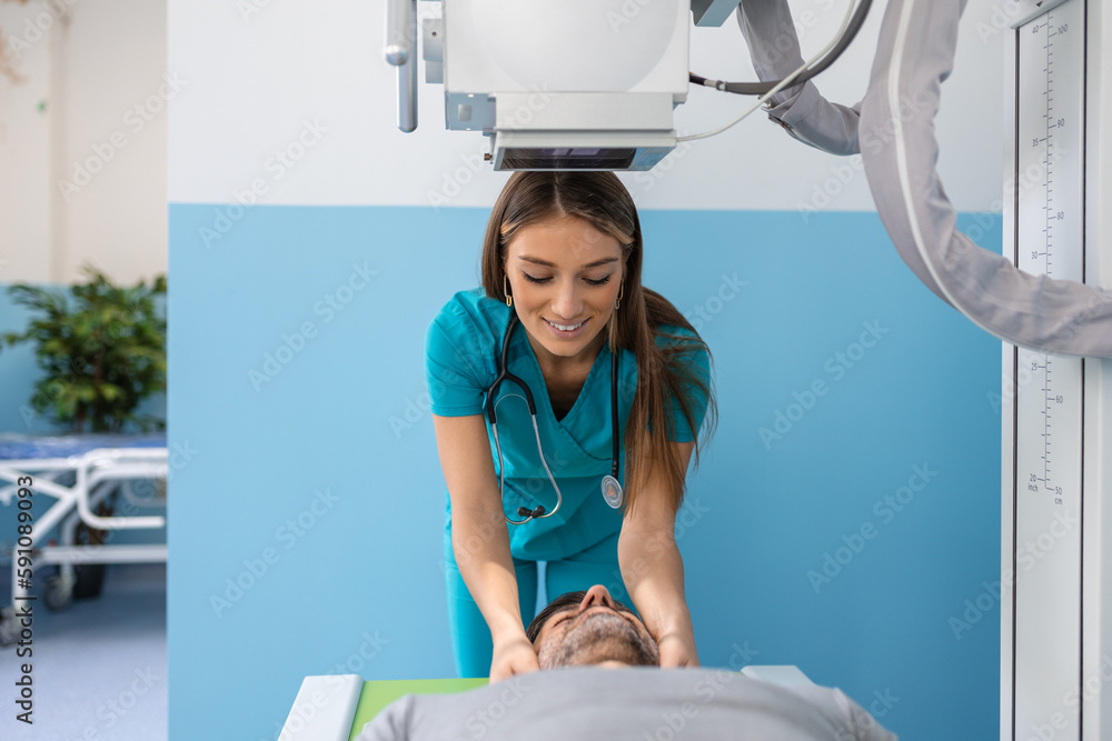 Male patient lying on bed while female nurse adjusting modern X-ray ...