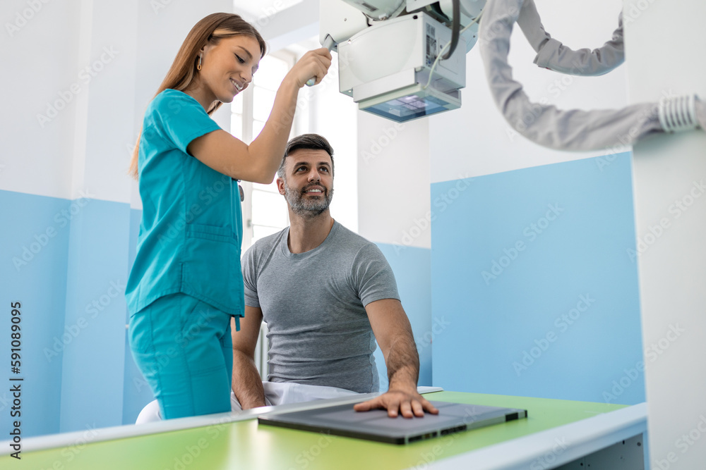 Female radiologist preparing patient for X-ray of hand near X-ray ...
