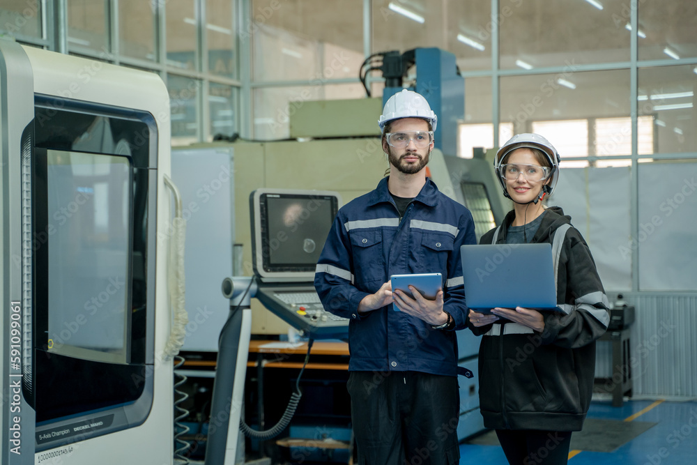 Engineer using laptop for programming modern robot arm in automated manufacturing industry ...