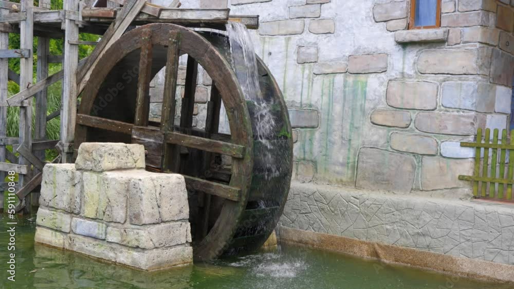 Large wooden wheel rotates under the pressure of water in an old ...