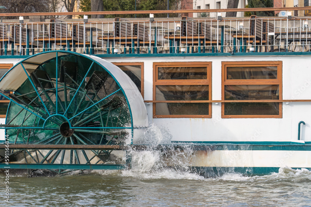 Water flows over the parts of the paddle wheel of a river steamer, a ...