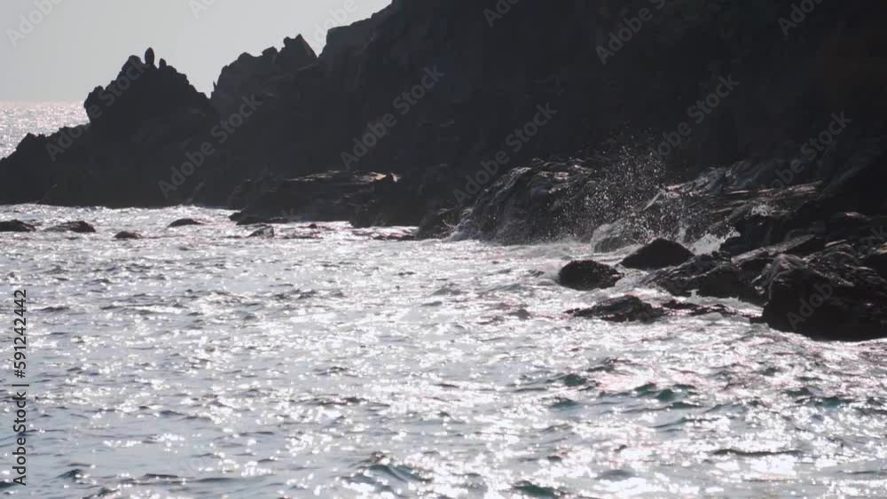 Slow motion shot of sea waves striking the rocks at the shore of ...