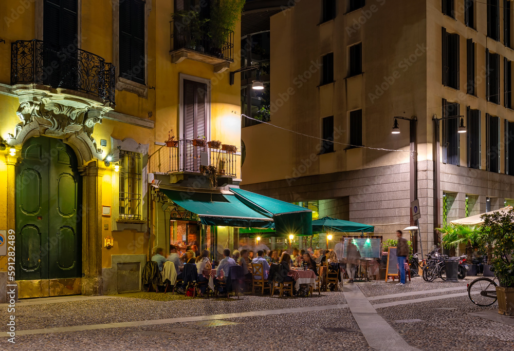 Old street with restaurant tables Milan, Italy. Night cityscape of ...