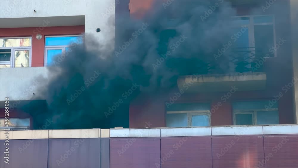 Front view: dark thick smoke from the fire is pouring out of the window ...
