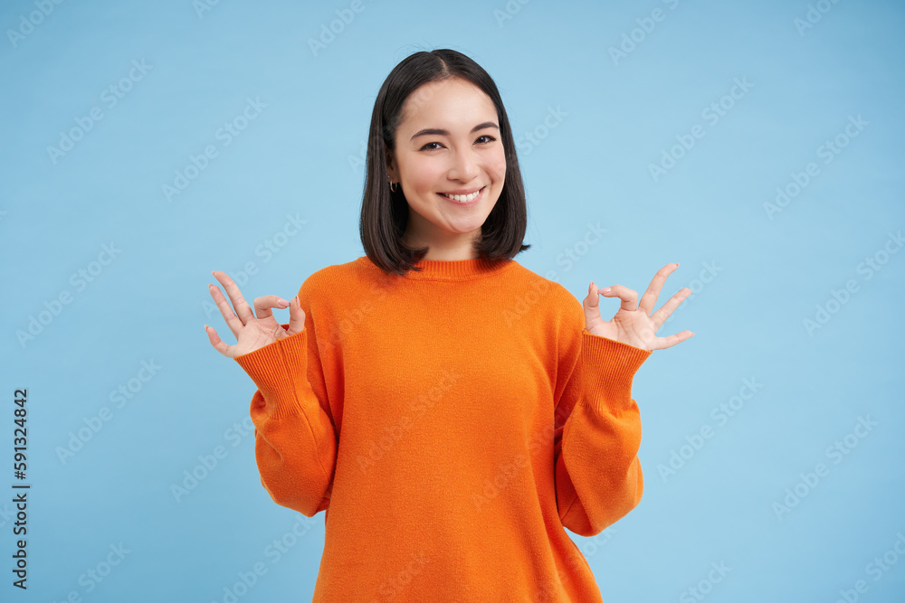 Everything ok. Smiling korean female model, shows okay, alright gesture ...