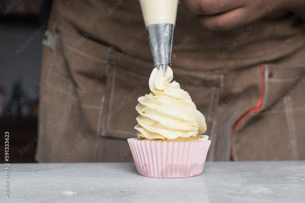 Piping buttercream on a vanilla cupcake, decorating cupcakes, hand ...