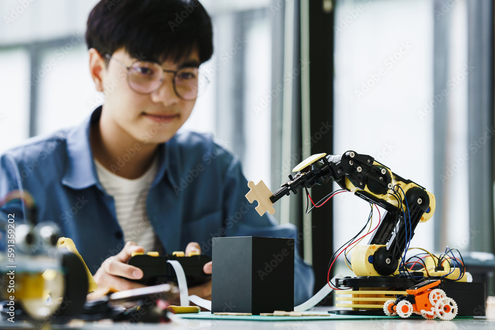 Asian teenager students doing or playing robot arm and robotic cars ...